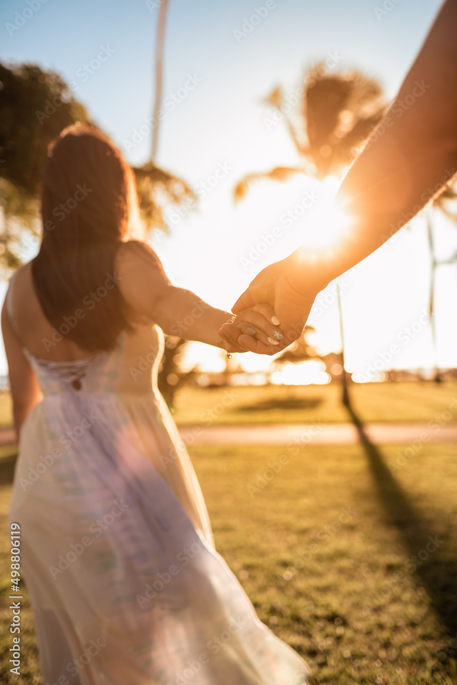 Come take my hand. Man and woman holding hands walking into the sunset ...