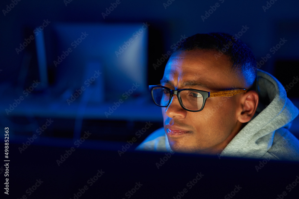 Taking a closer look at things. Shot of a young male hacker cracking a ...