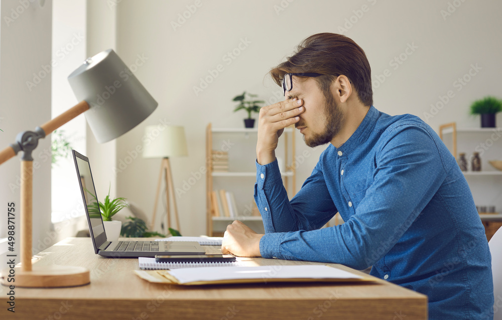 Tired man who feels stressed with documents and paperwork and has eye ...