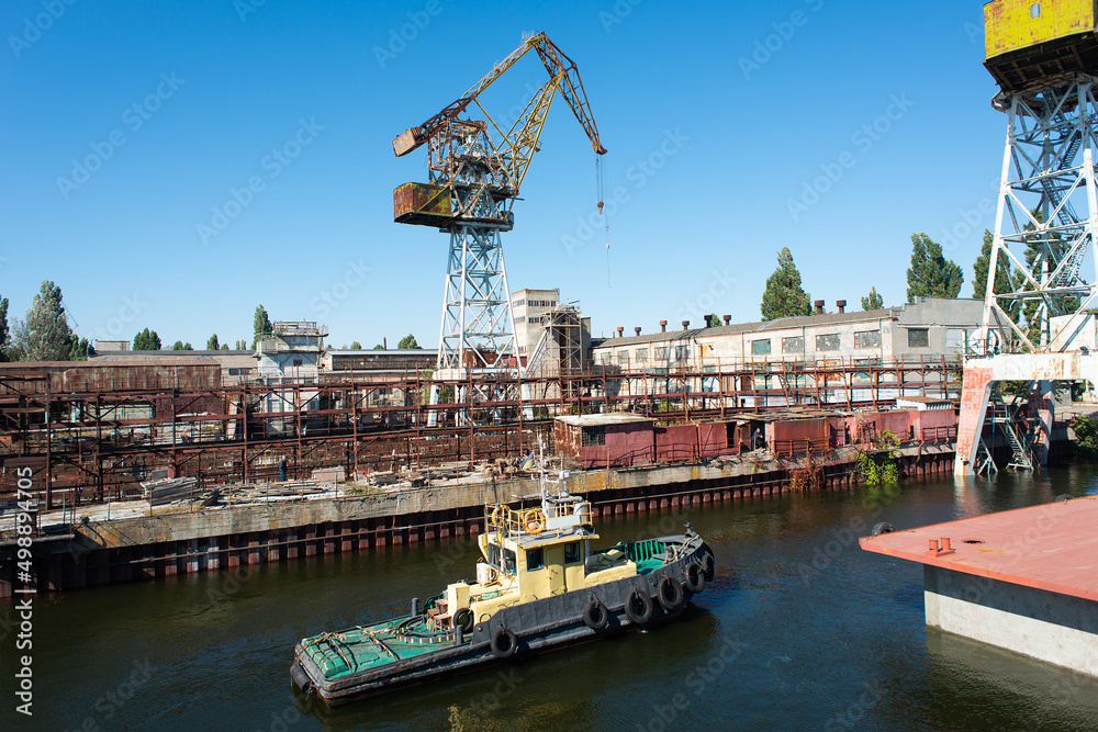a river tug hauls a floating barge out of a dry dock at a shipyard ...