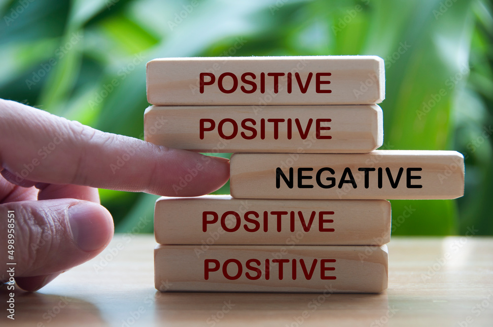 Hand pushing out negative out from positive - text on wooden blocks ...