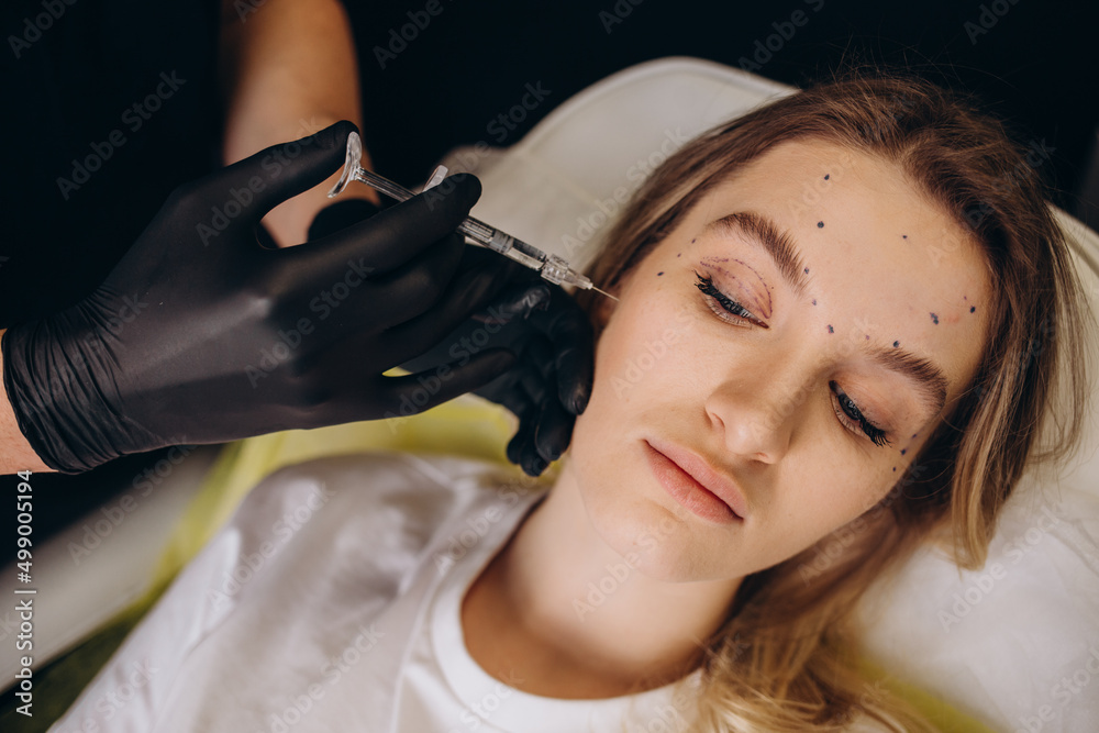 Beautician doctor with botulinum toxin syringe making injection to to ...