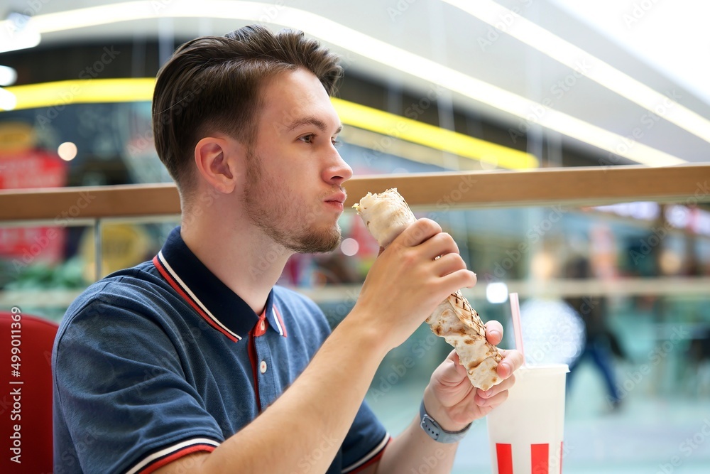 Portrait of young handsome man, guy is sitting in restaurant eating ...
