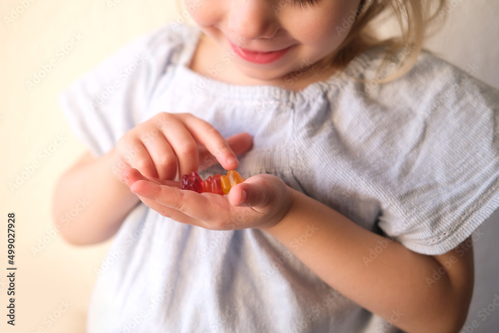 small child, blonde girl 3 years old wants to eat gelatinous sweets ...