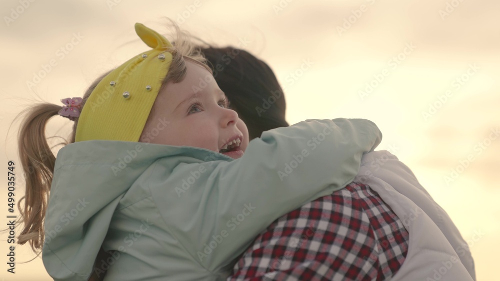 Young mom, kid, daughter are hugging in spring in park. Child smiles ...