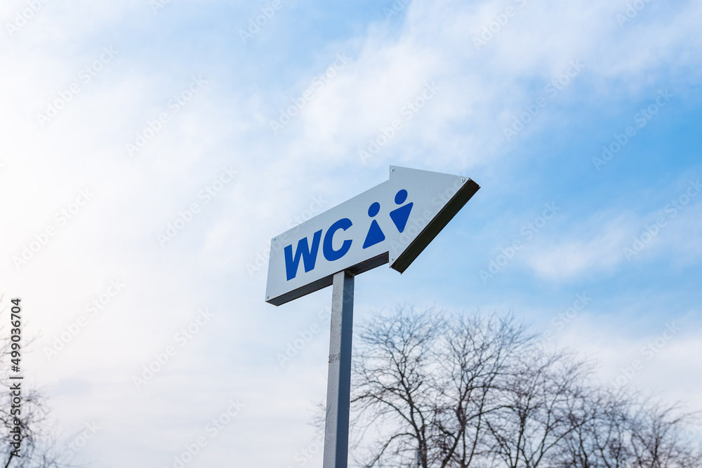 arrow shaped wc signboard on sky background, male and female public ...
