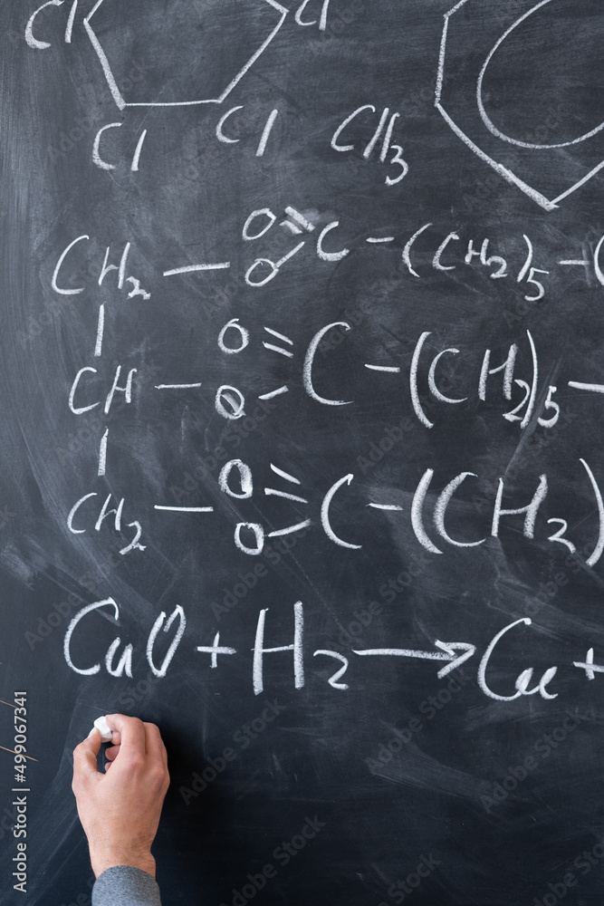 male hand drawing with chalk formulas and elements on the blackboard ...
