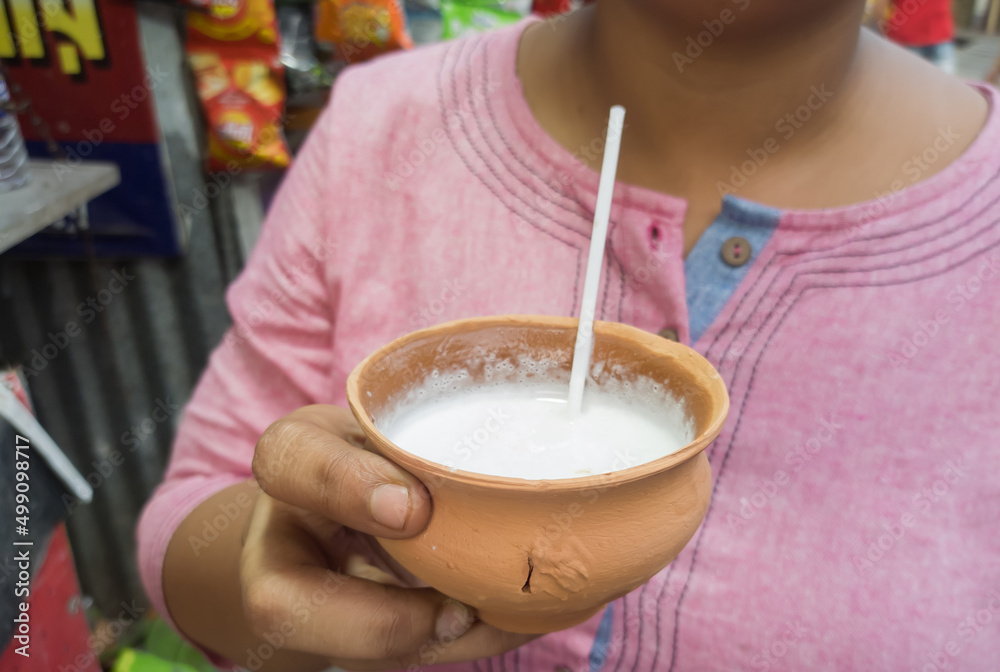 girl drinking lassi in traditional earthen clay pot. lassi is made of ...