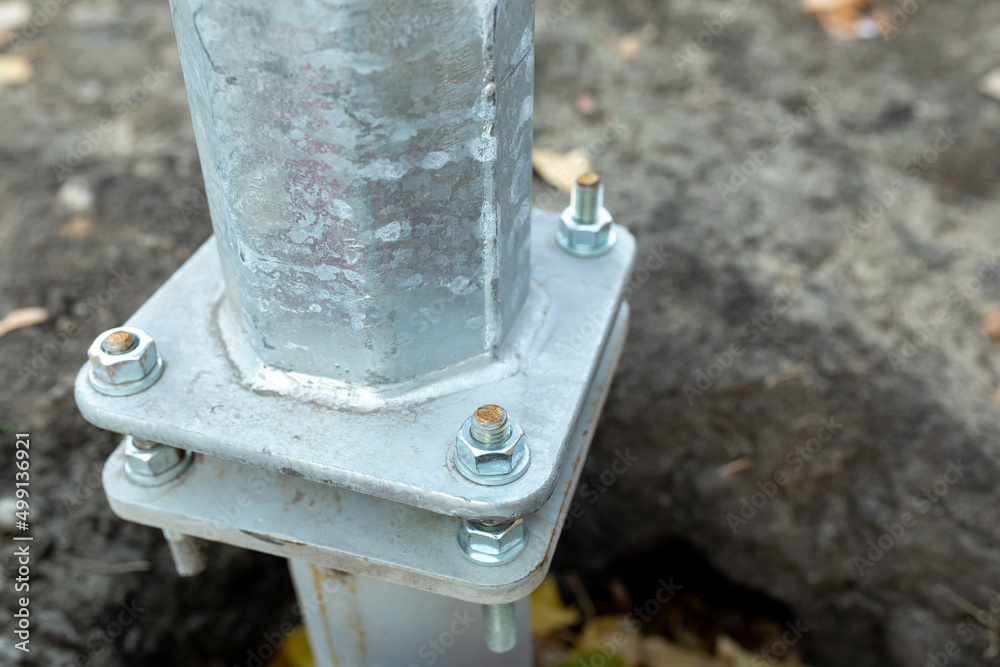 Metal pillar fastened to basement with anchor bolts and nuts. Support ...