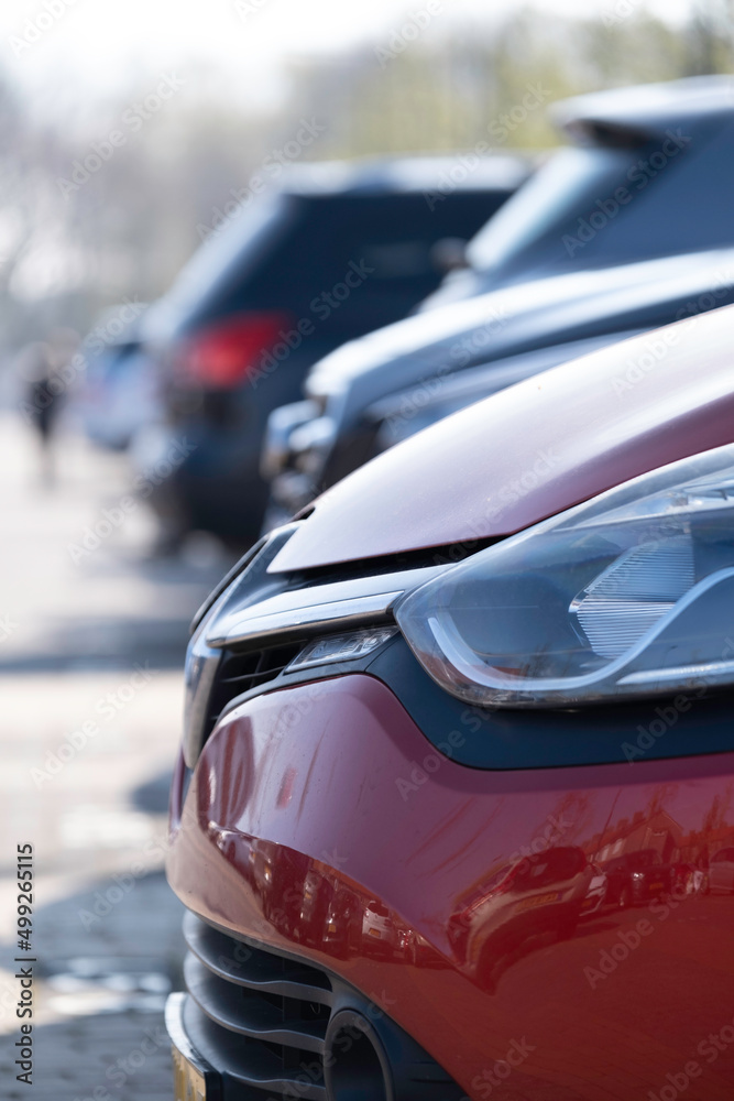 Many cars parked next to each other in a row in a parking lot. Focus on ...