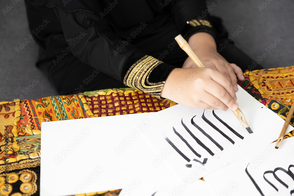 close up muslim girl hands writing Arabic text with bamboo pens and ...