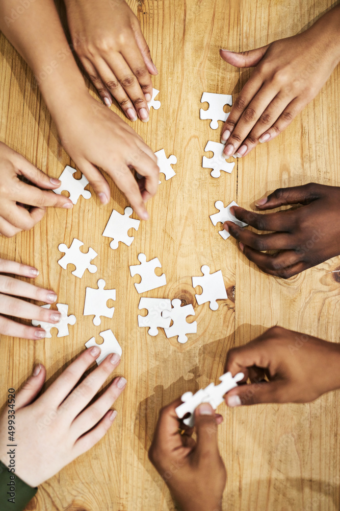 Problem solving like pros. Shot of a group of people building a puzzle ...