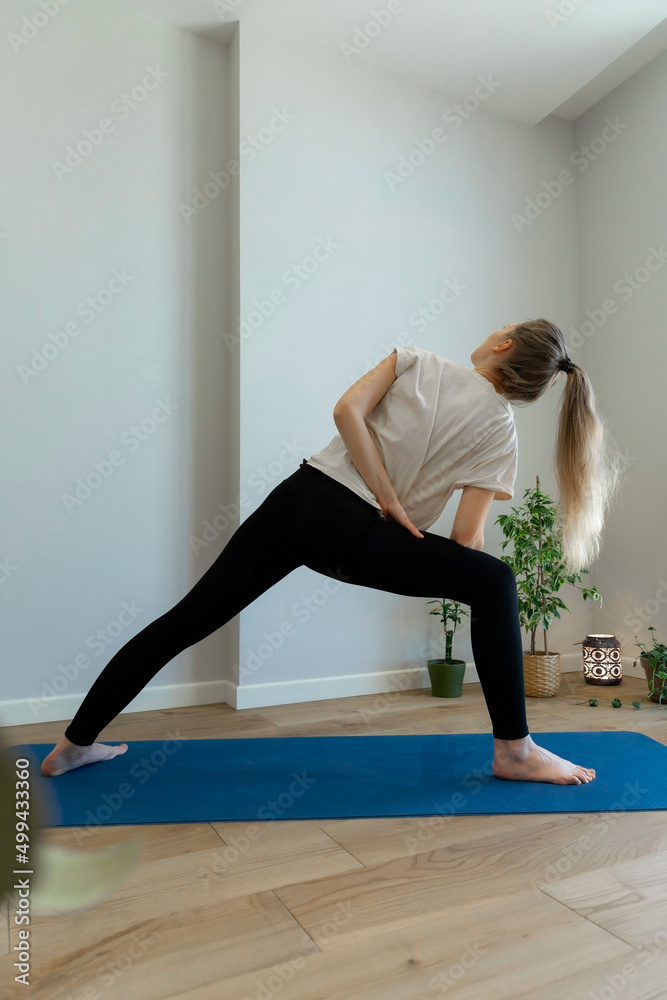 flexible young woman is doing standing twisting pose, stretching her ...
