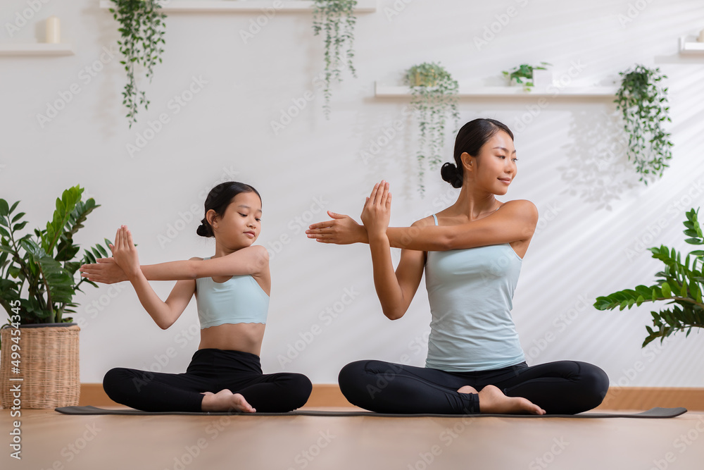Foto de Asian mom and little girl exercise stretching muscle together ...