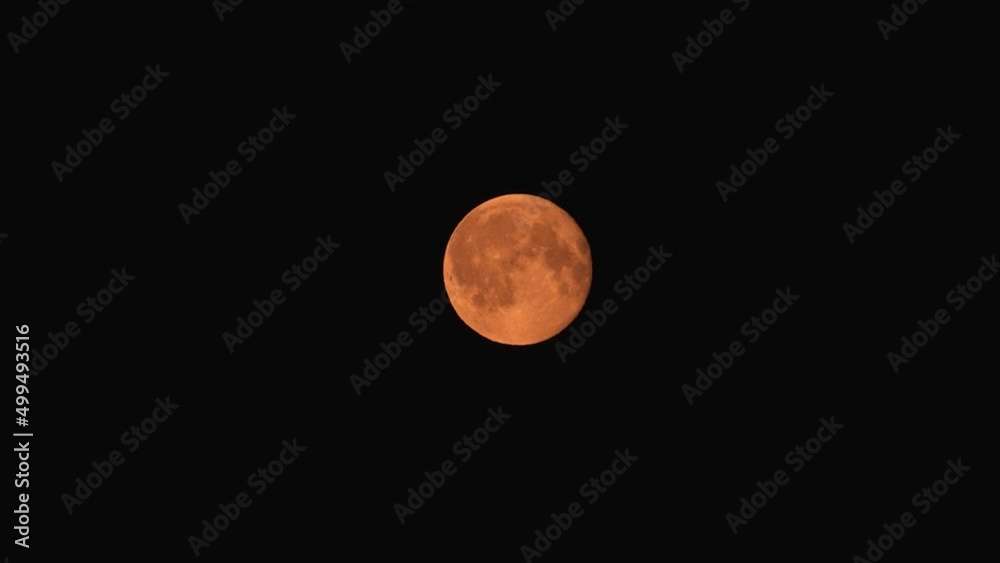 The red full moon floats across the black sky. A rare natural ...
