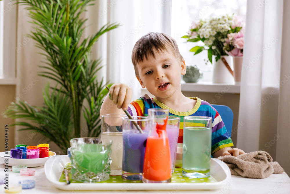 Cute baby boy learning mixing different colors with water and paint in ...