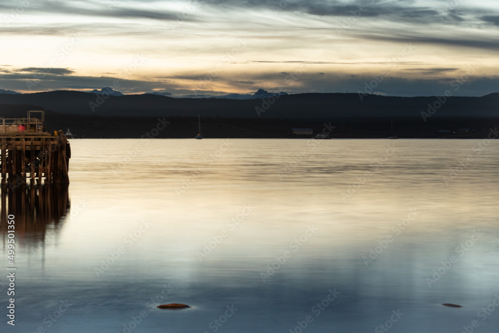 costa de mar en atardecer con montañas y nubes, mar con reflejos del ...