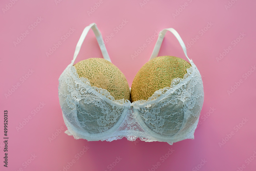 Check those melons. Studio shot of melons in a bra against a pink ...