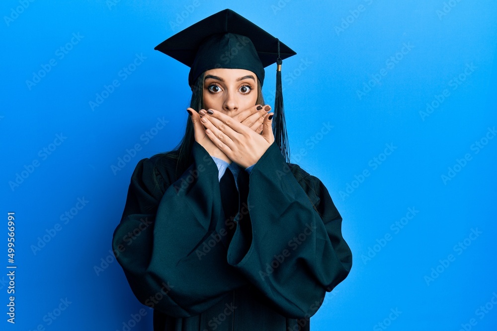 Beautiful brunette young woman wearing graduation cap and ceremony robe ...