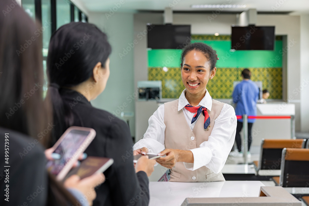 Smiling multiracial woman in check-in counter taking passport for ...