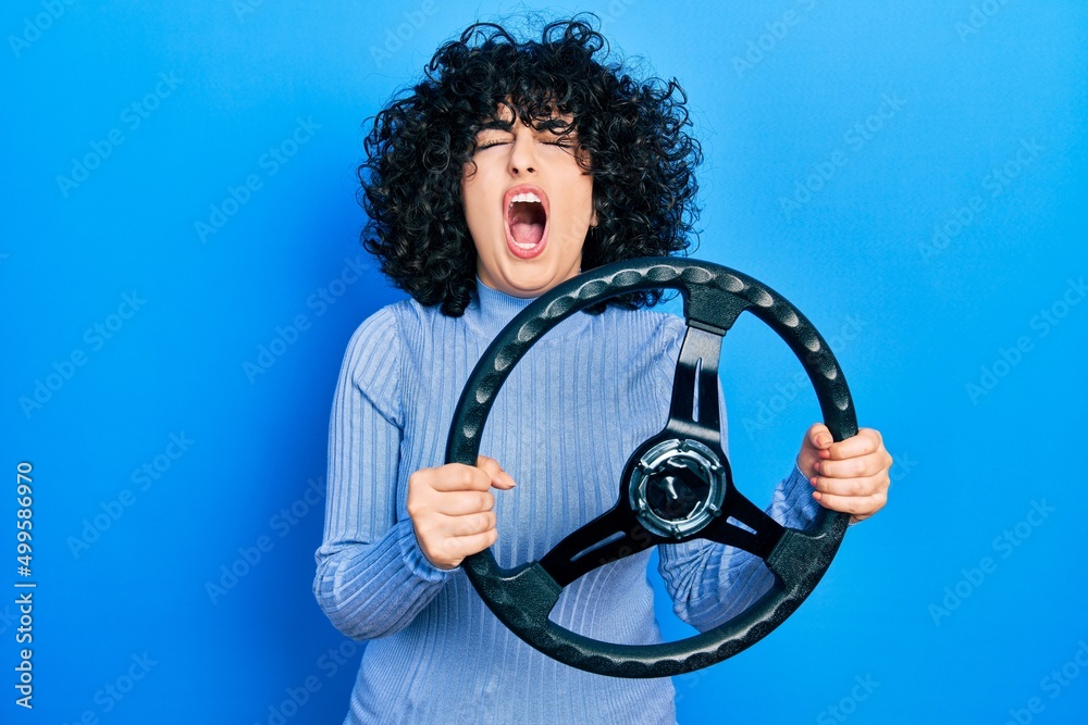 Young middle east woman holding steering wheel angry and mad screaming ...