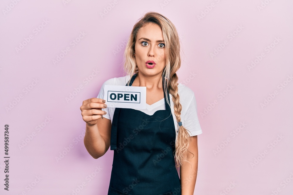 Beautiful young blonde woman wearing waitress apron holding open banner ...