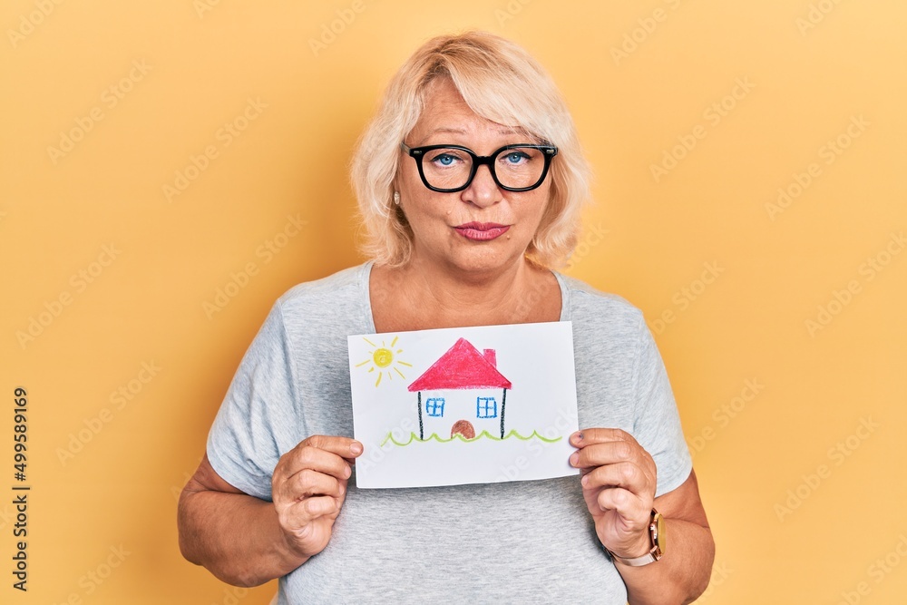 Middle age blonde woman holding house draw depressed and worry for ...