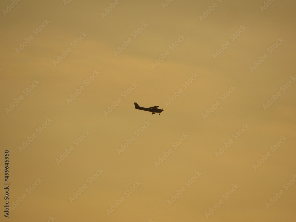 Silueta de avioneta volando al atardecer Stock Photo | Adobe Stock