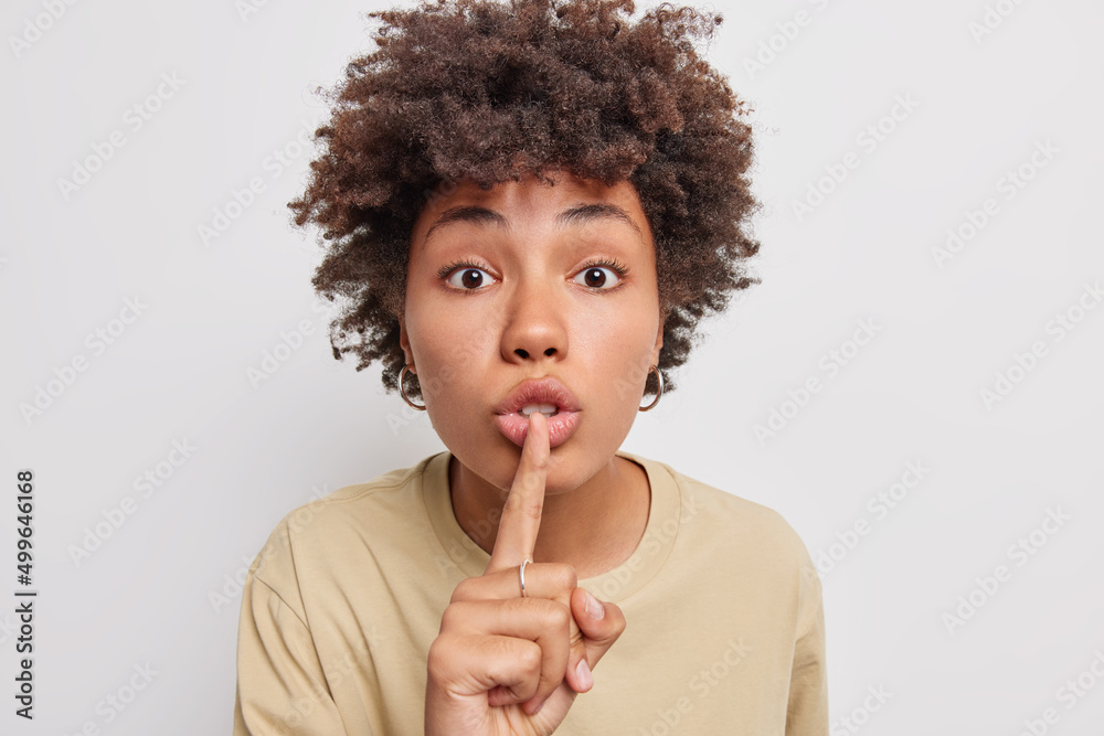 African American woman shows hush sign has mysterious expression asks ...