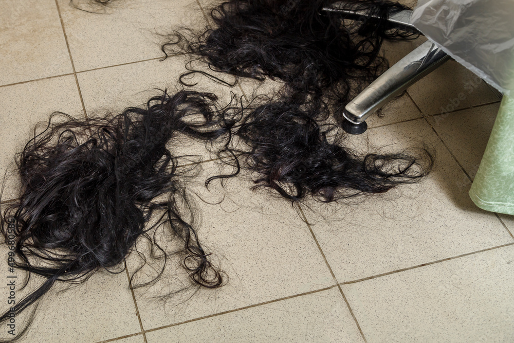 Cropped long female black hair on the floor next to the hairdresser's ...