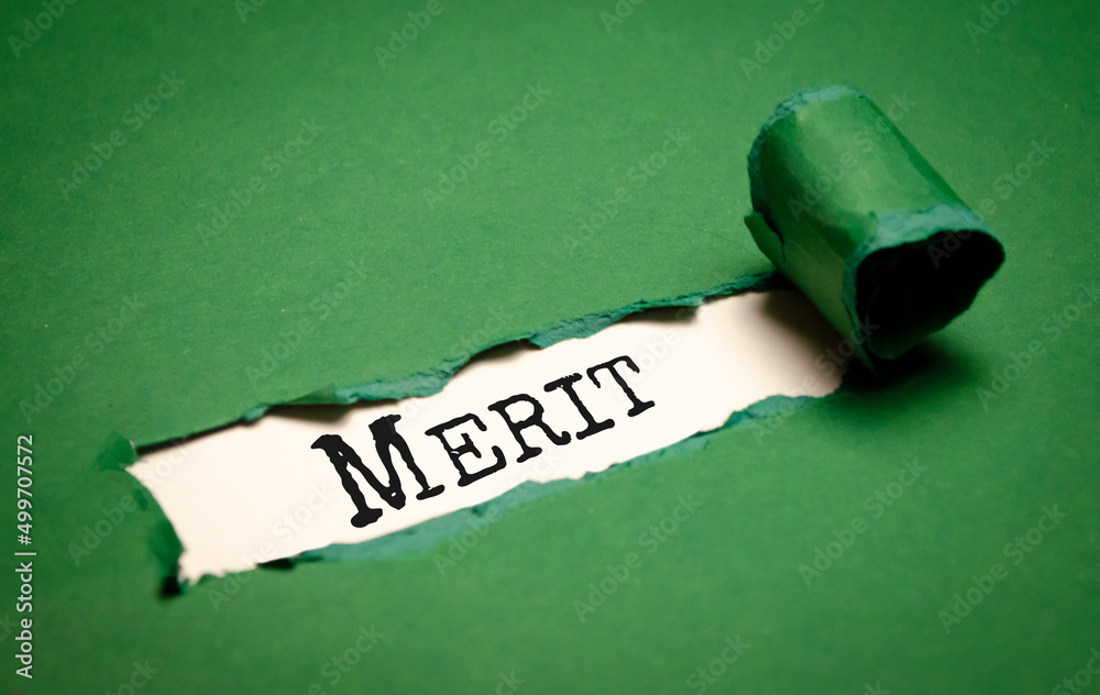 Top view of white torn paper and the text merit on a yellow background ...
