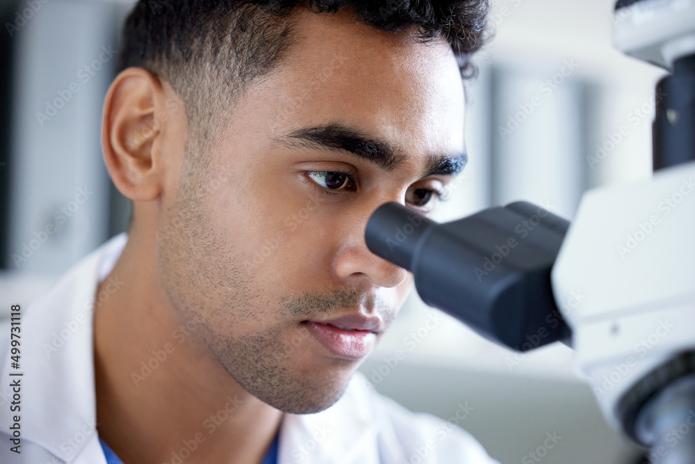 What do we have here. Shot of a young man using a microscope in a lab ...