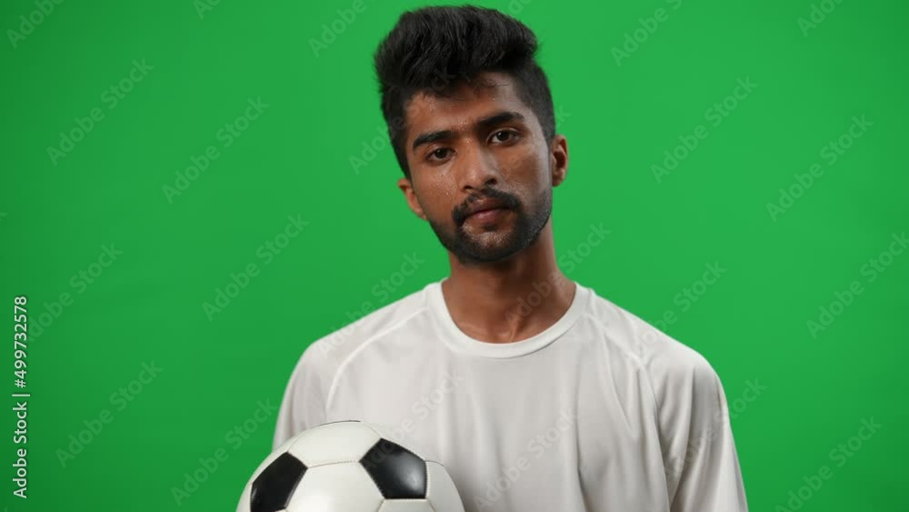 Young perspiring Middle Eastern footballer wiping sweat off forehead ...