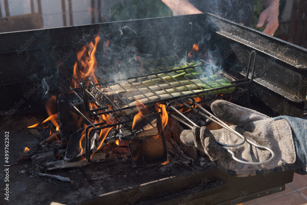 A man cooking calçots, a young Catalan onion. Preparing a "Calçotada ...