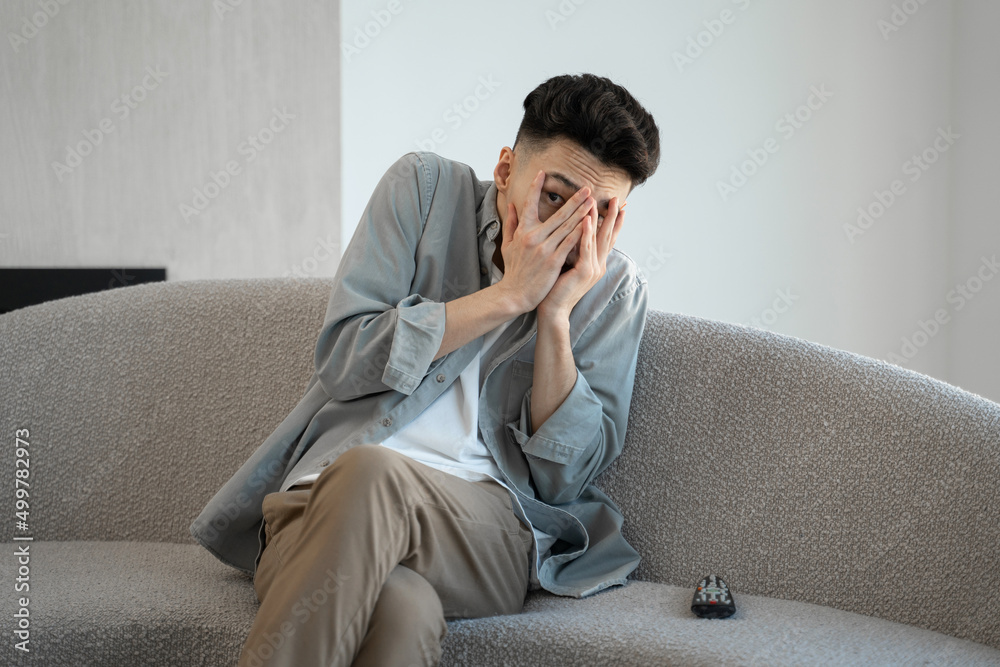 Young Asian man watches horror movie on TV getting scared and covering ...