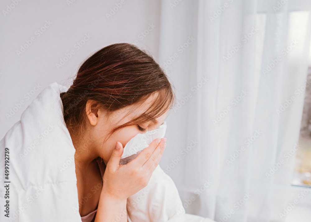 A cold girl blows her nose in a white rag on white background. Rhinitis ...