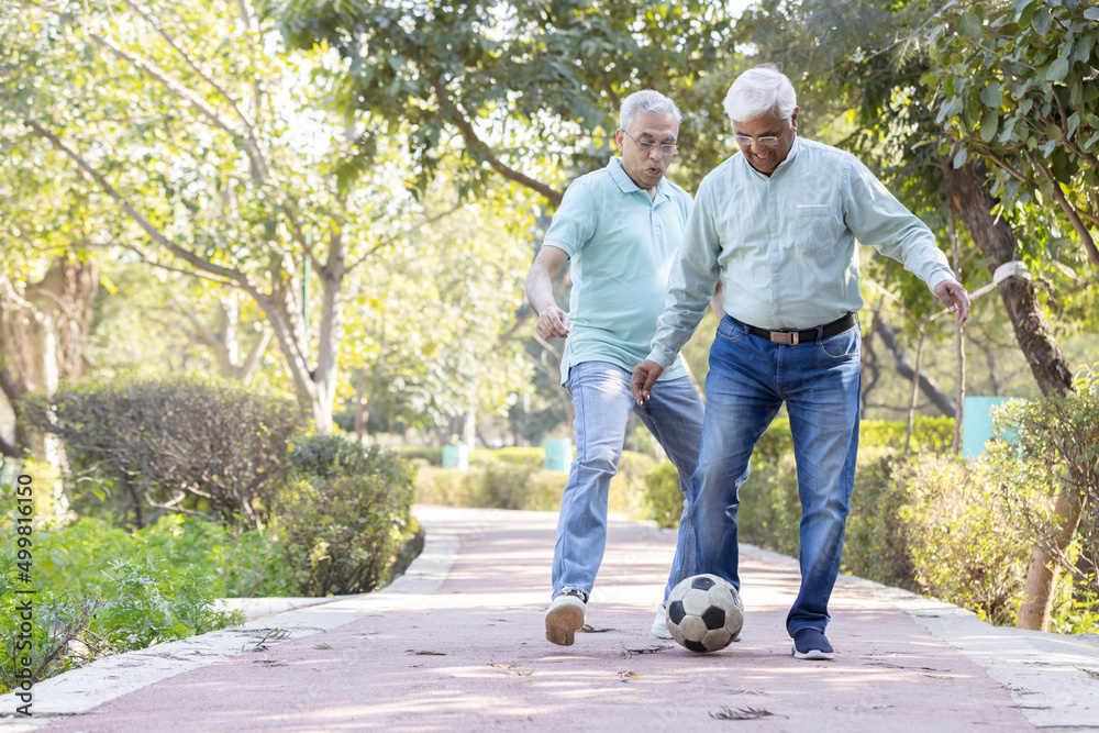 Two senior man having fun while playing football at park Stock Photo ...