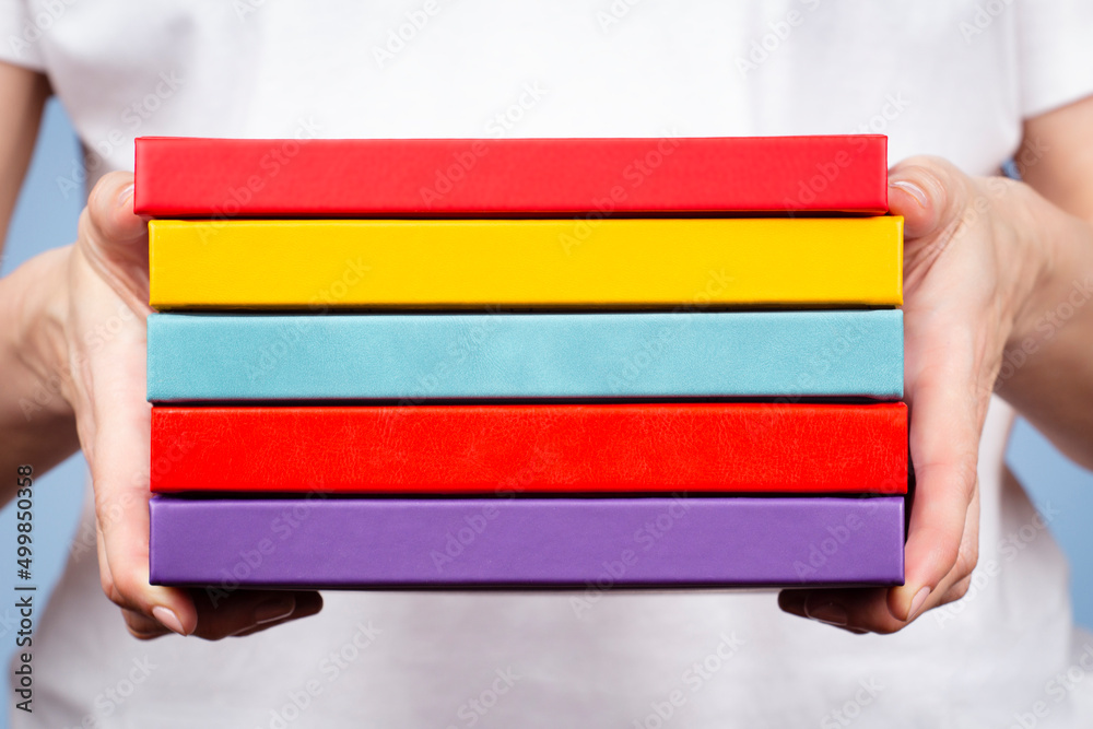 Female hands holding pile of books over light blue background ...