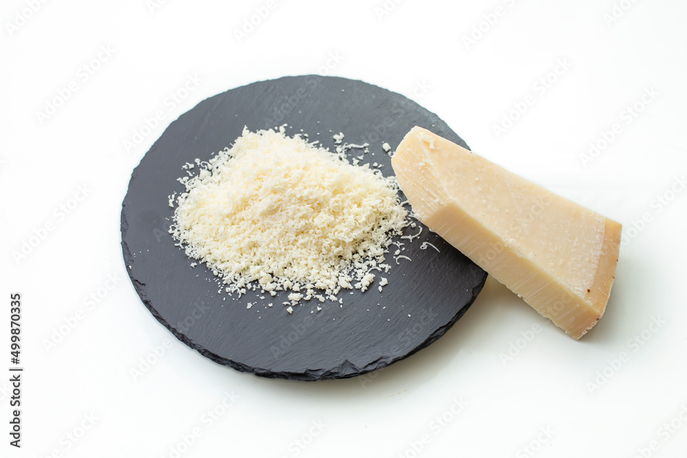 grated parmesan on a black stone tile, isolated on white background ...