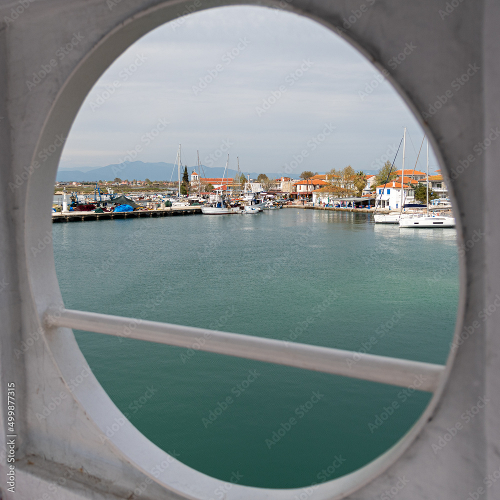 Scenic view through the ferries round window of the Greek ship port ...