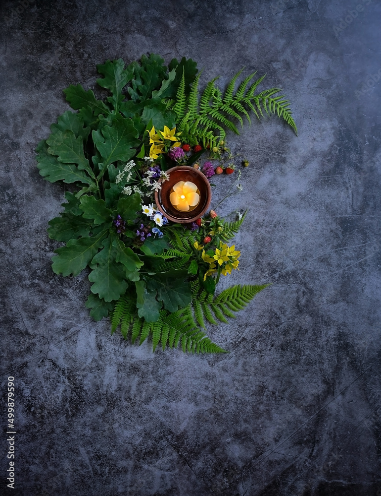 wiccan altar with candle, flowers, oak and fern leaves on dark abstract ...