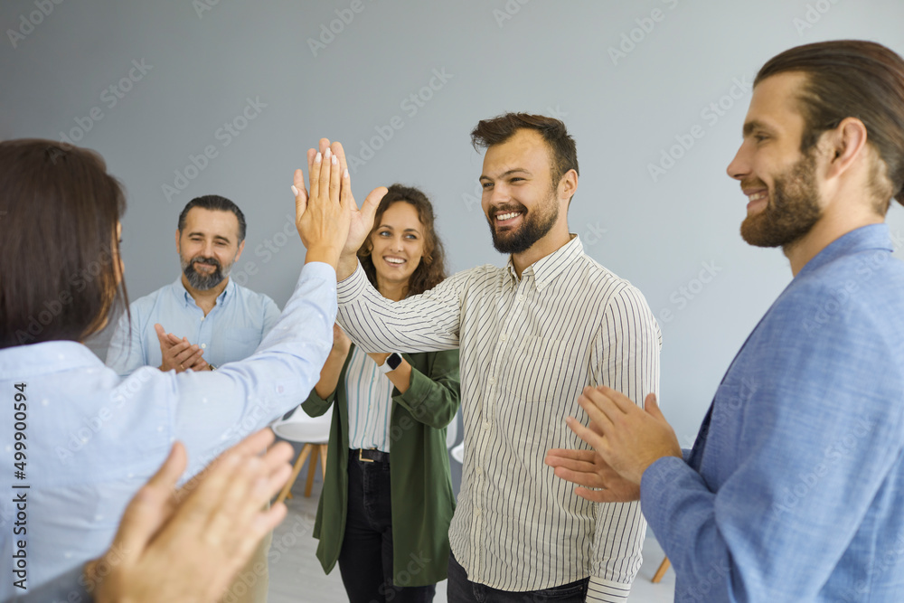 Woman gives five to her happy successful male colleague to applause of ...