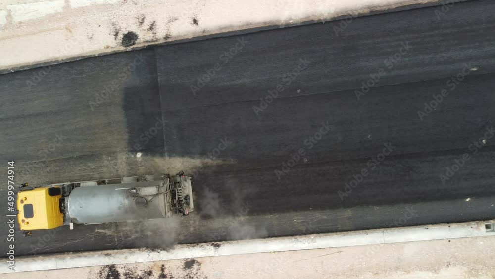 yellow truck pouring bitumen over a new road. Aerial drone shot. Road ...