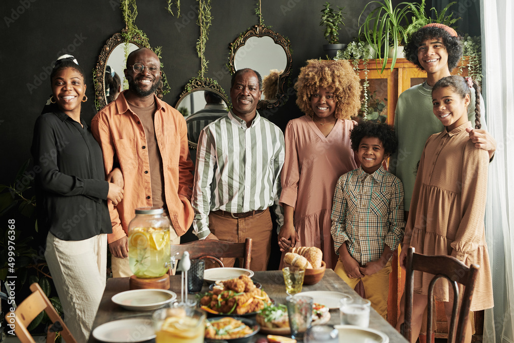 Portrait of big African family smiling at camera standing near dining ...
