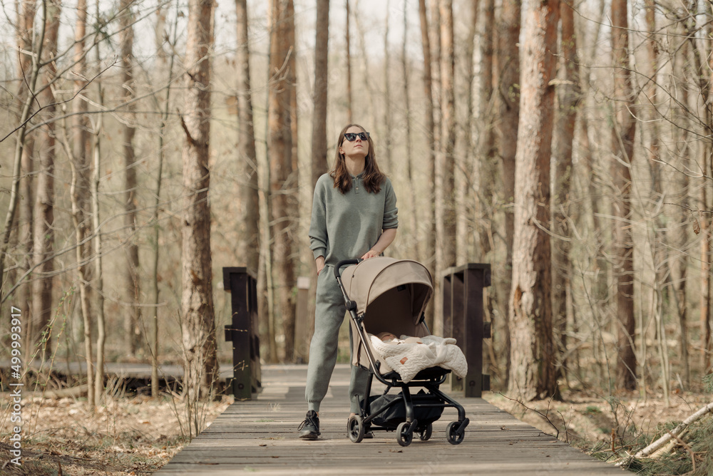 Mom is walking on a wooden walkway with a child who is sleeping in the ...