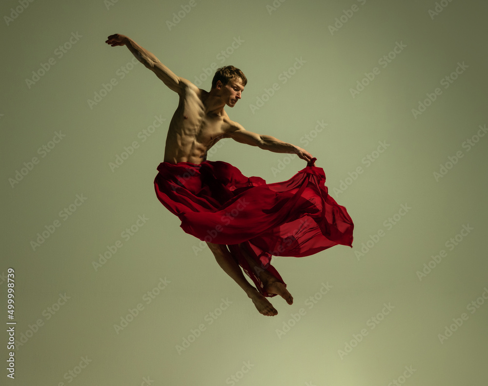 One young muscled man, flexible ballet dancer in action with red fabric ...