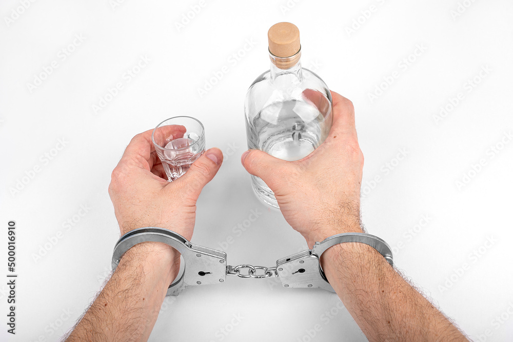 The concept of male alcohol addiction. Handcuffed hands holding a ...