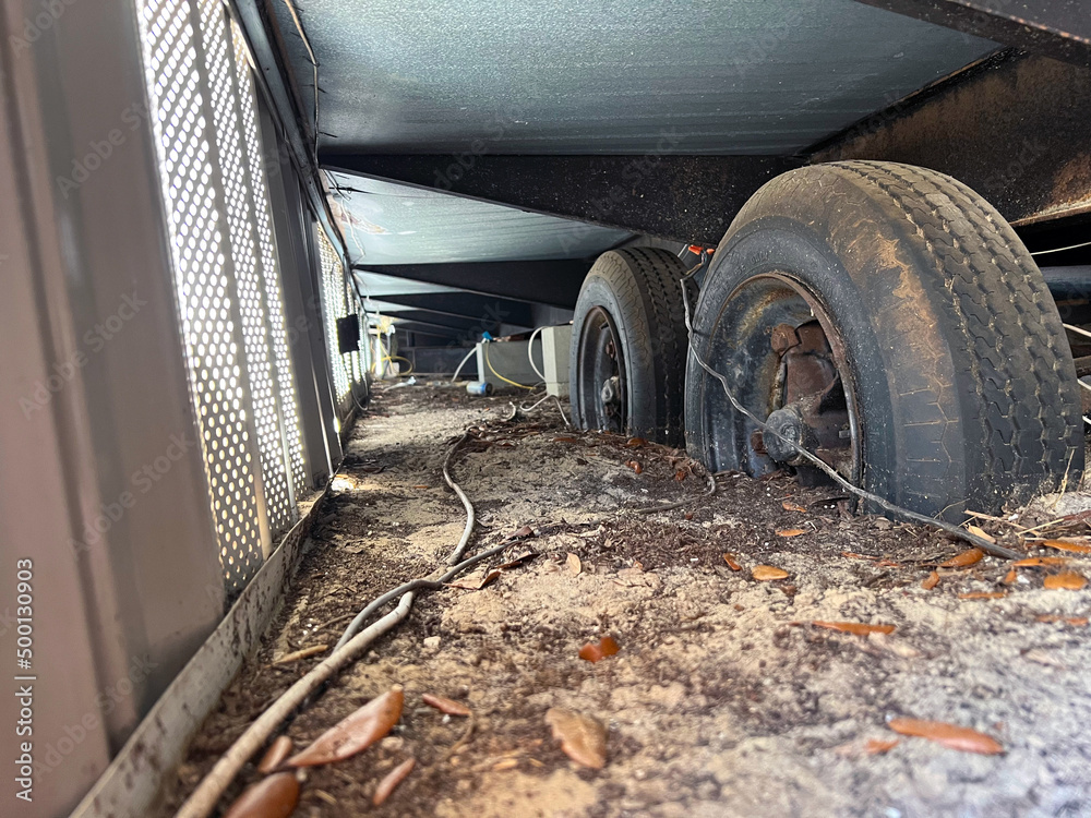 Crawlspace underneath manufactured home with old destroyed wheels on ...
