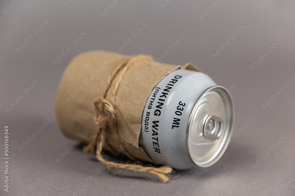 Cylindrical can of drinking water in front of the gray background ...