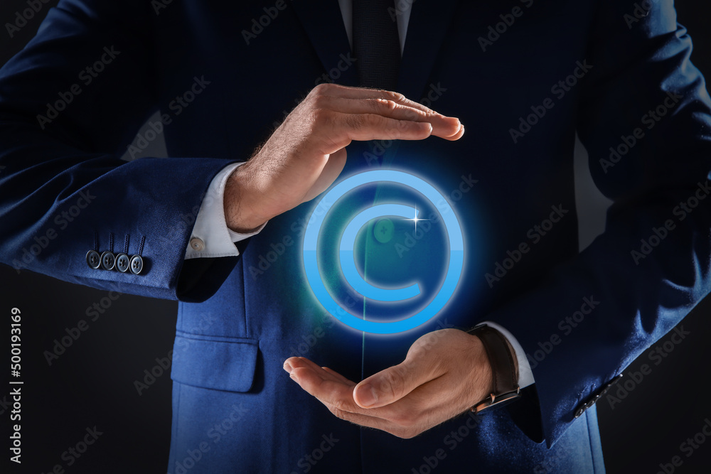 Man holding virtual icon of copyright symbol on dark background ...